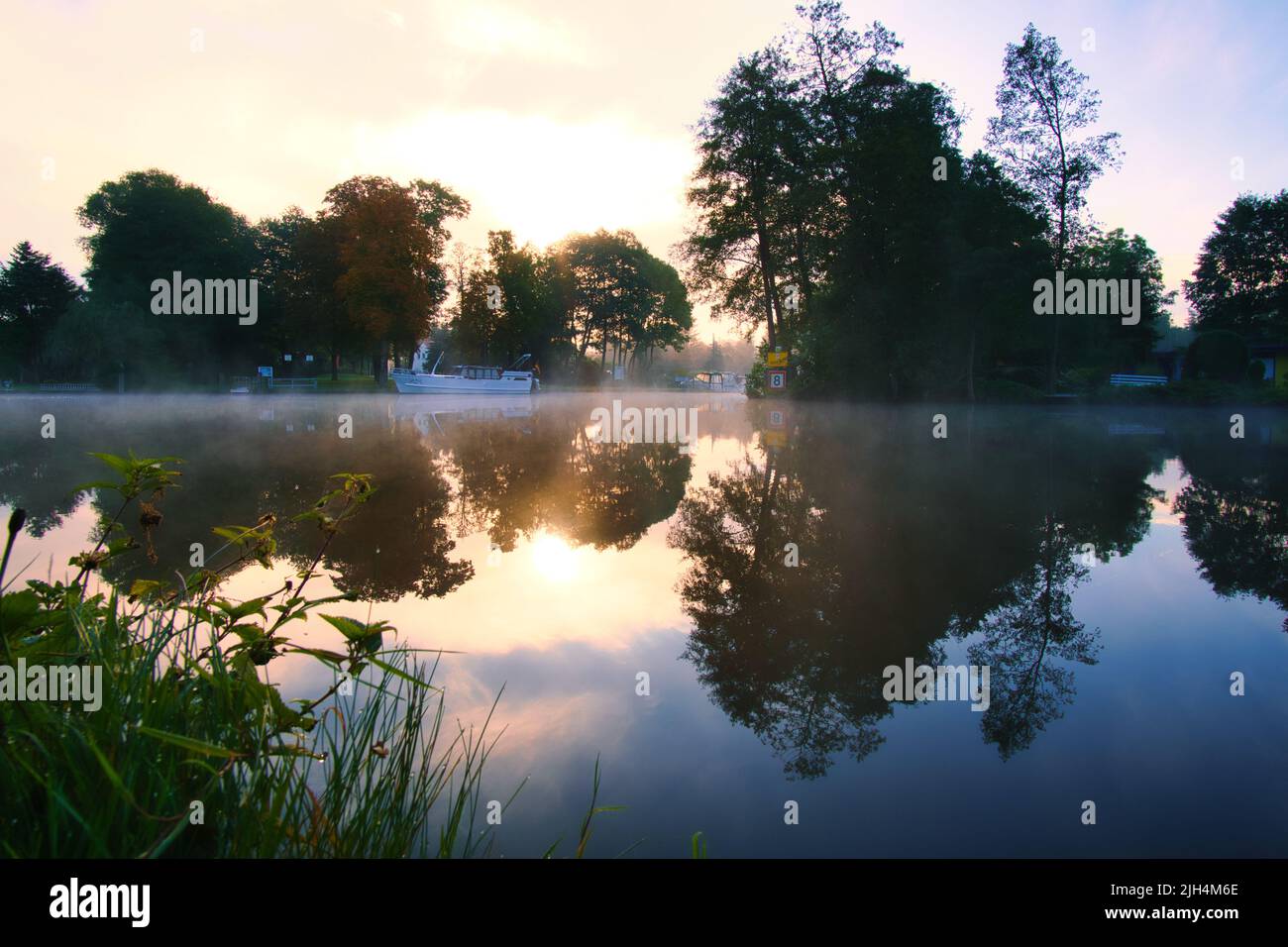 A sunrise at dawn, with fog on the river and warm light atmosphere ...