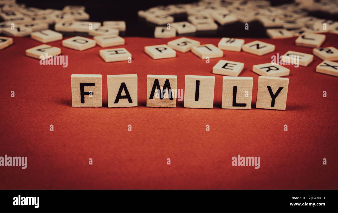 Word "Family" composed of wooden tiles with letters on a red felt ...