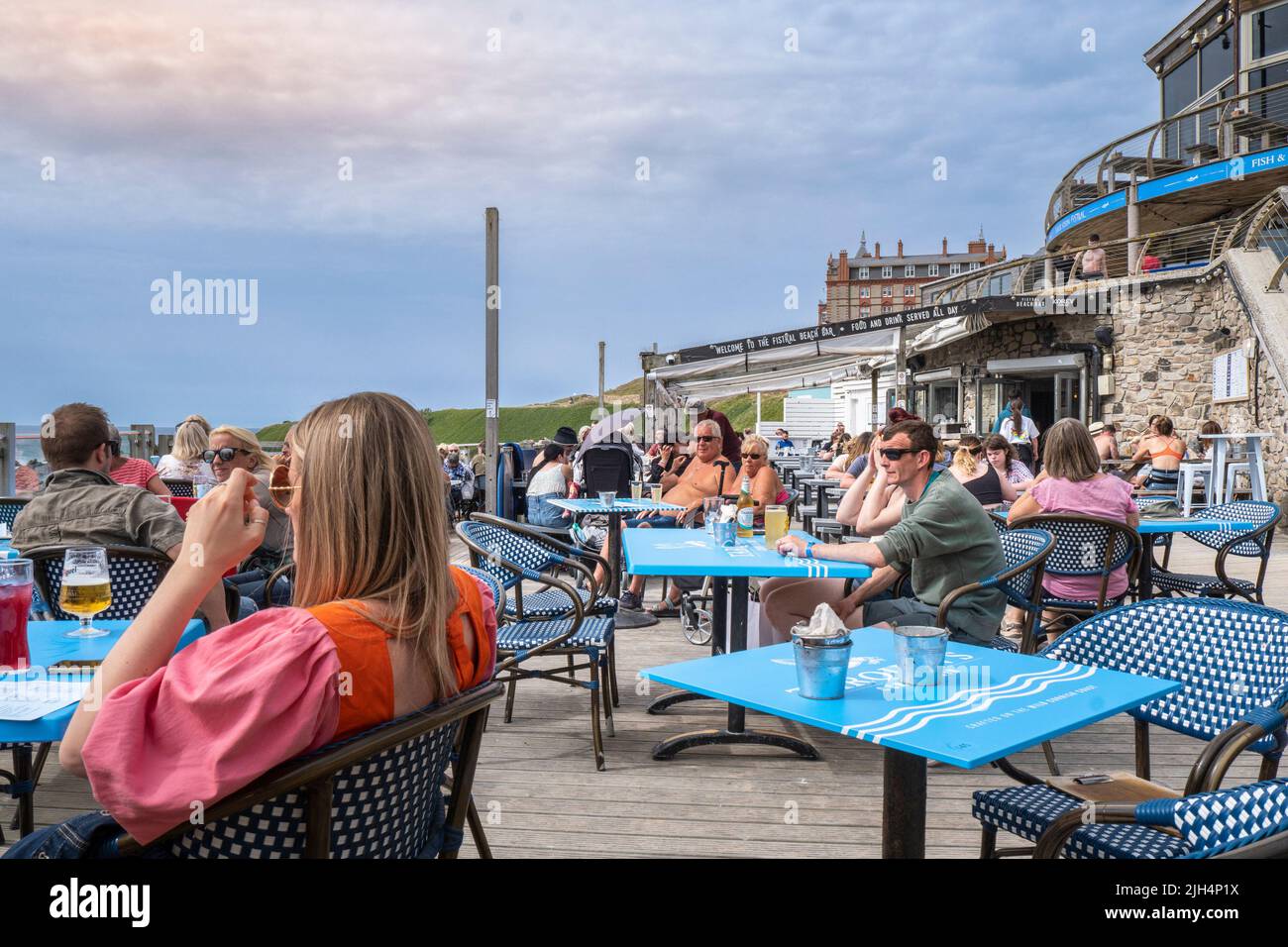 Holidaymakers relaxing on the outdoor decking area of the Fistral Beach ...