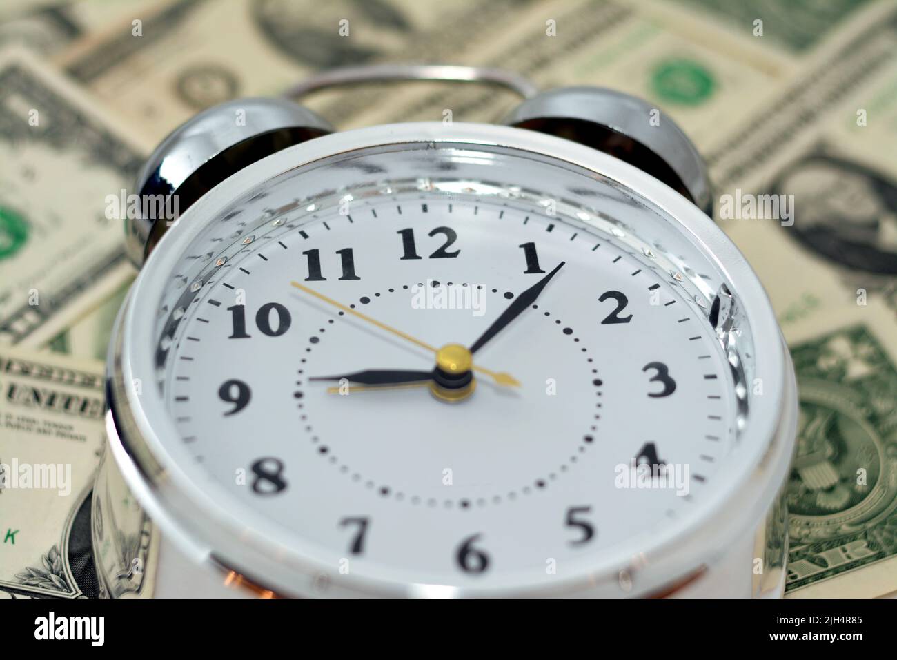 An alarm clock on a background of blurred American money banknote ...