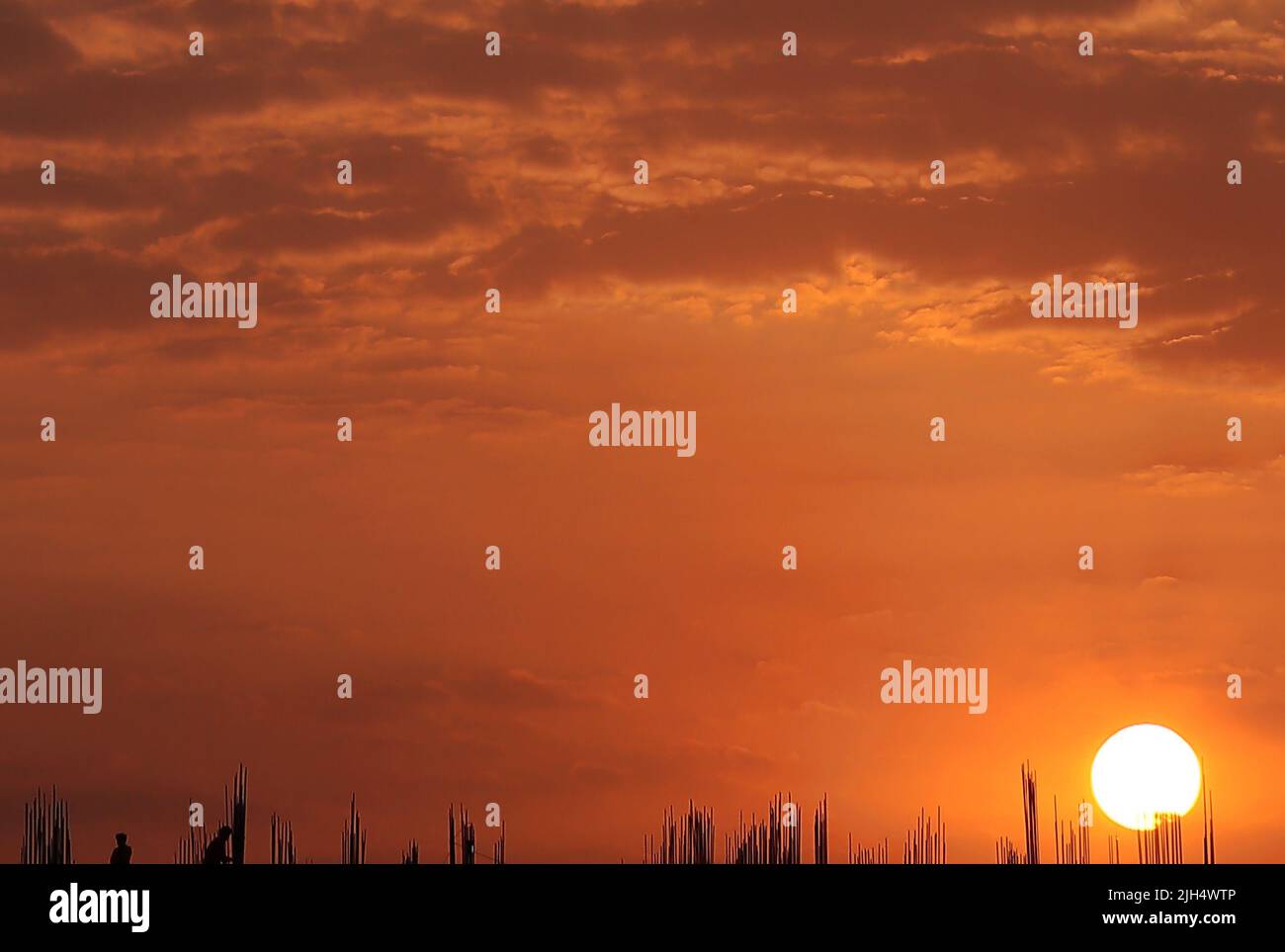 Silhouette of a building under construction against the rising Sun ...