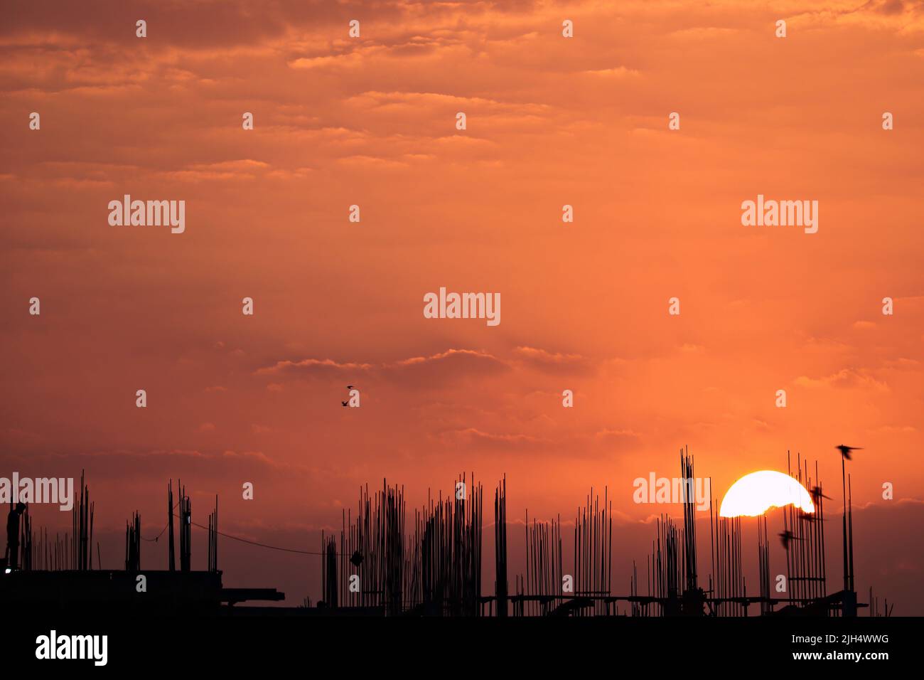 Silhouette of a building under construction against the rising Sun ...