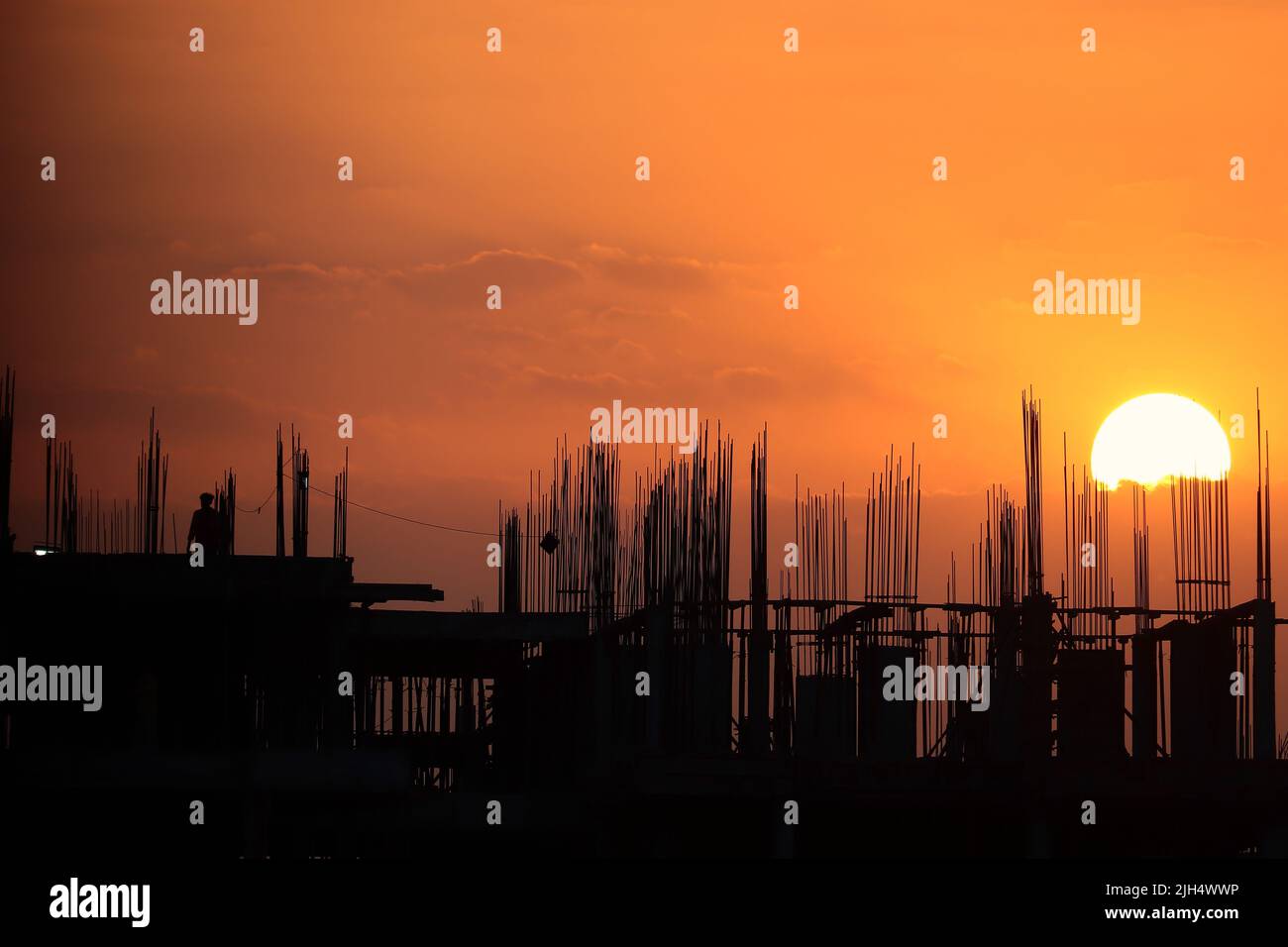 Silhouette of a building under construction against the rising Sun ...