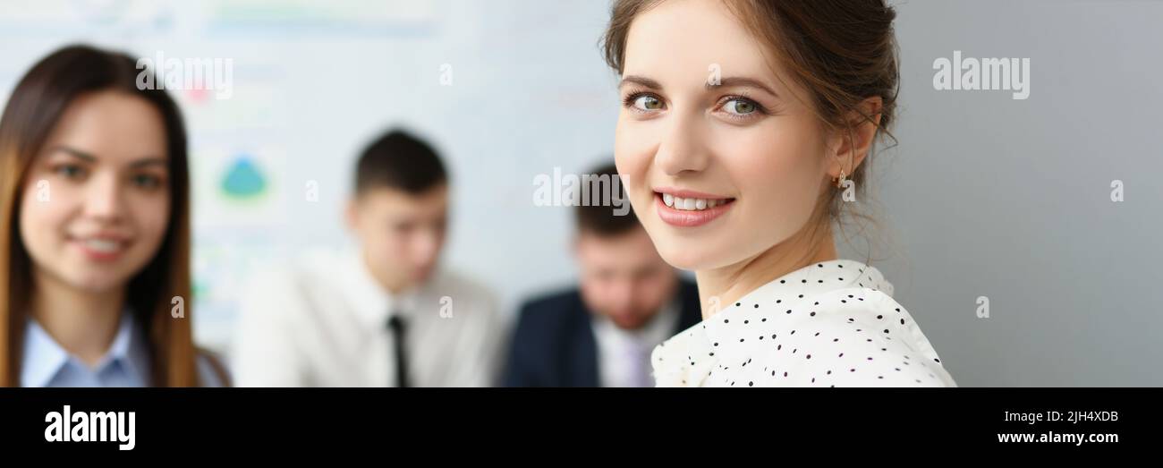 Smart woman sitting in big modern office with colleagues and smile at ...