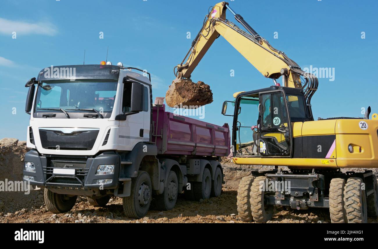 Excavator loads trucks with excavation Stock Photo - Alamy
