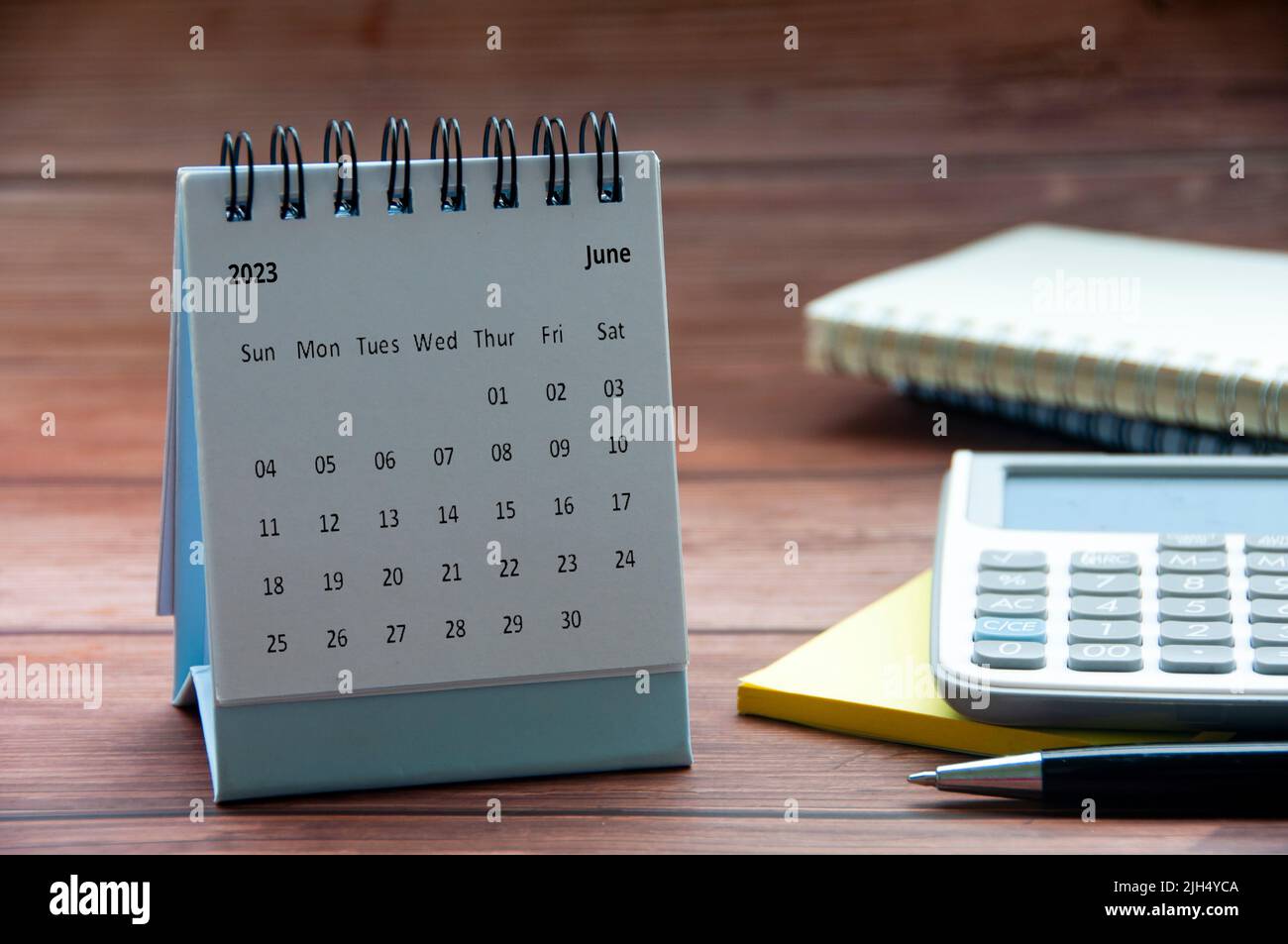 June 2023 white desk calendar on wooden table with notepad, calculator ...