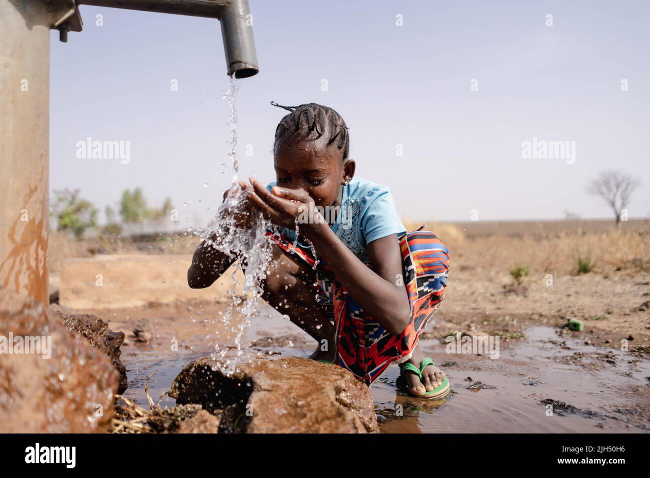 Little African girl splashing herself with copious amounts of clean ...