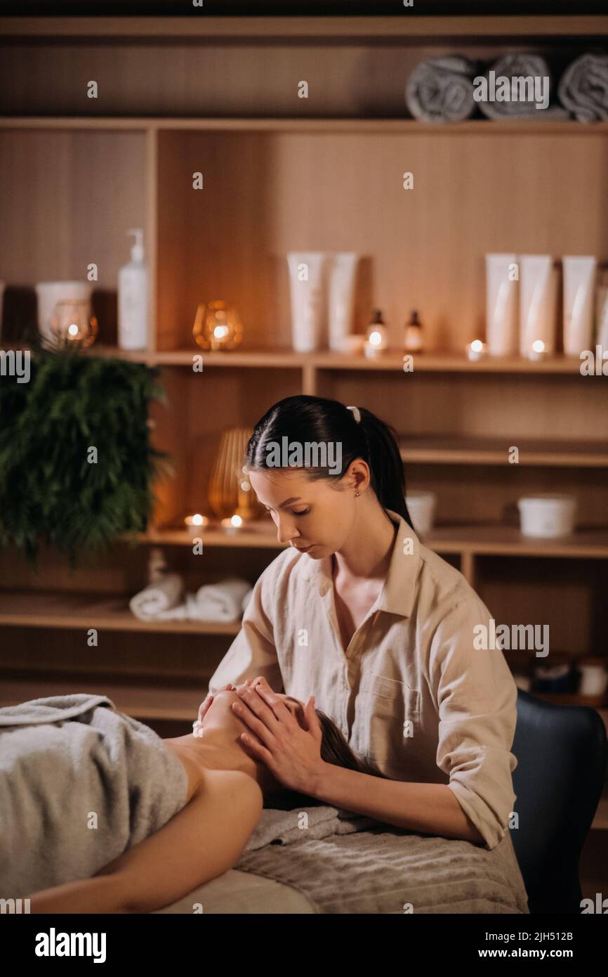 A cosmetologist girl does a facial and neck massage to a girl in the ...