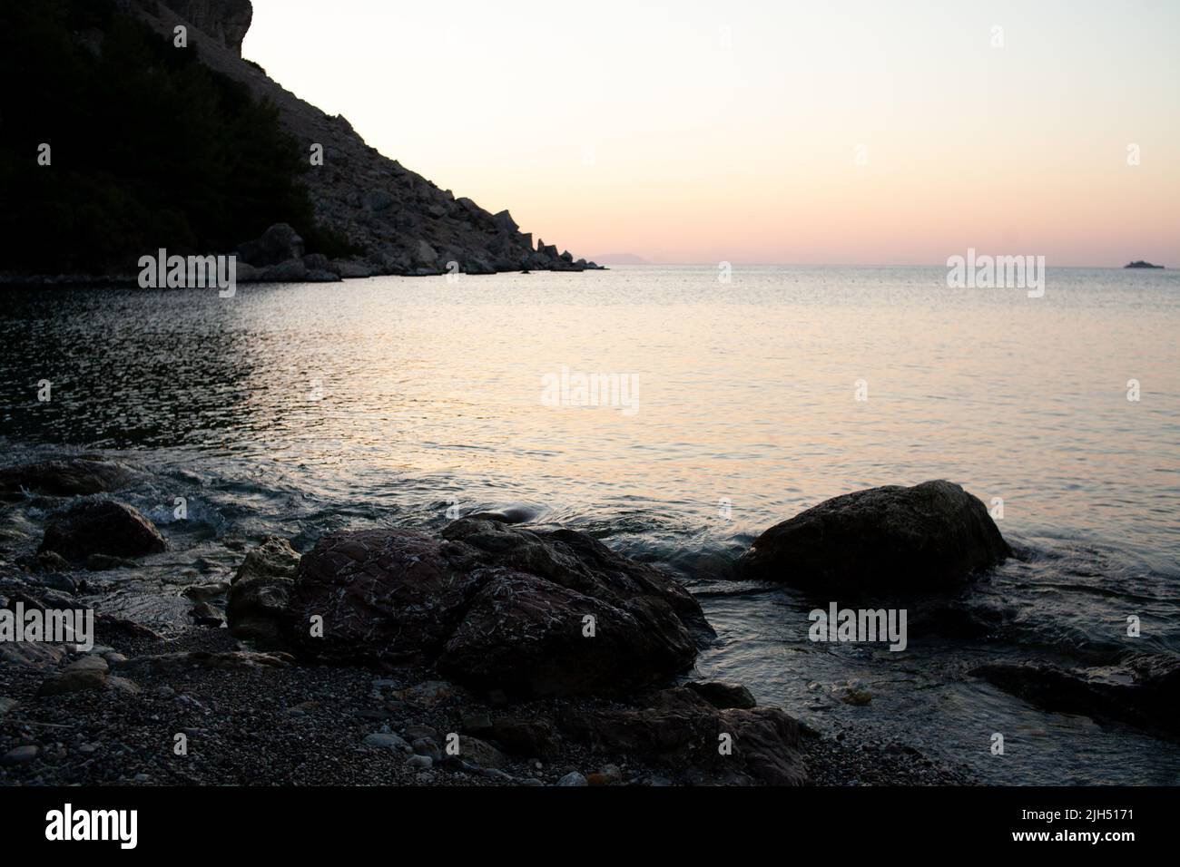 Sunrise over mountain rock in sea water. Sunrise seascape in calm sea ...