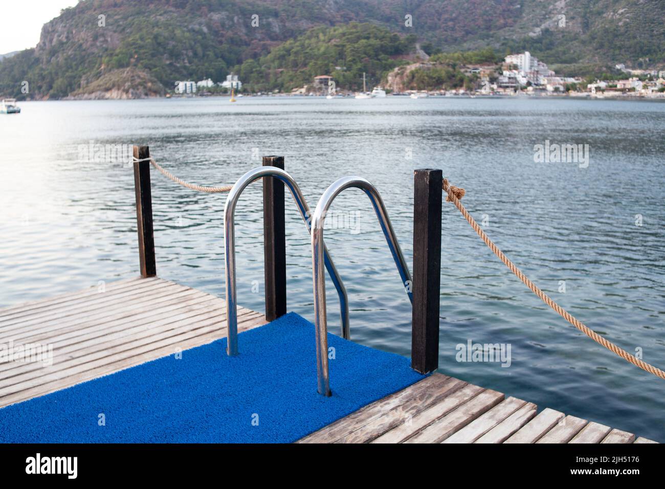 Metal handrails and ladder to descend into the water on a wooden pier ...