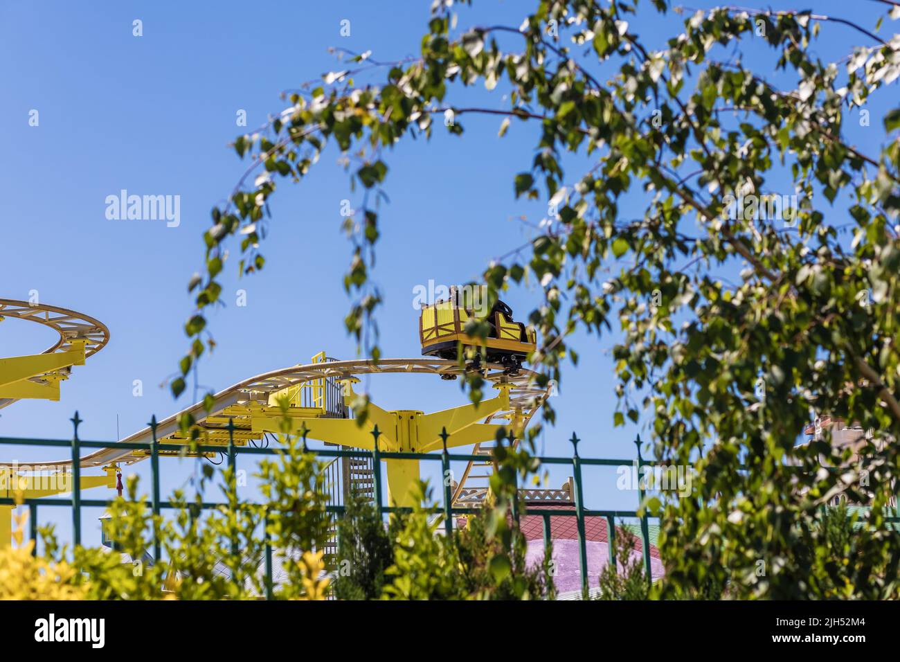 Yellow extreme attraction is located behind trees and a fence under ...