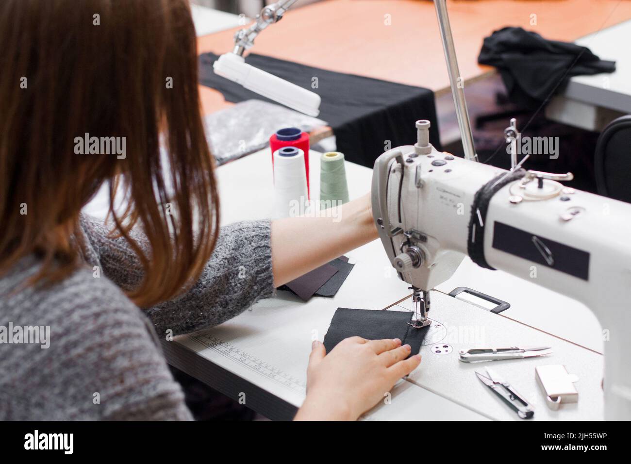 Seamstress sewing at machine, back view Stock Photo - Alamy