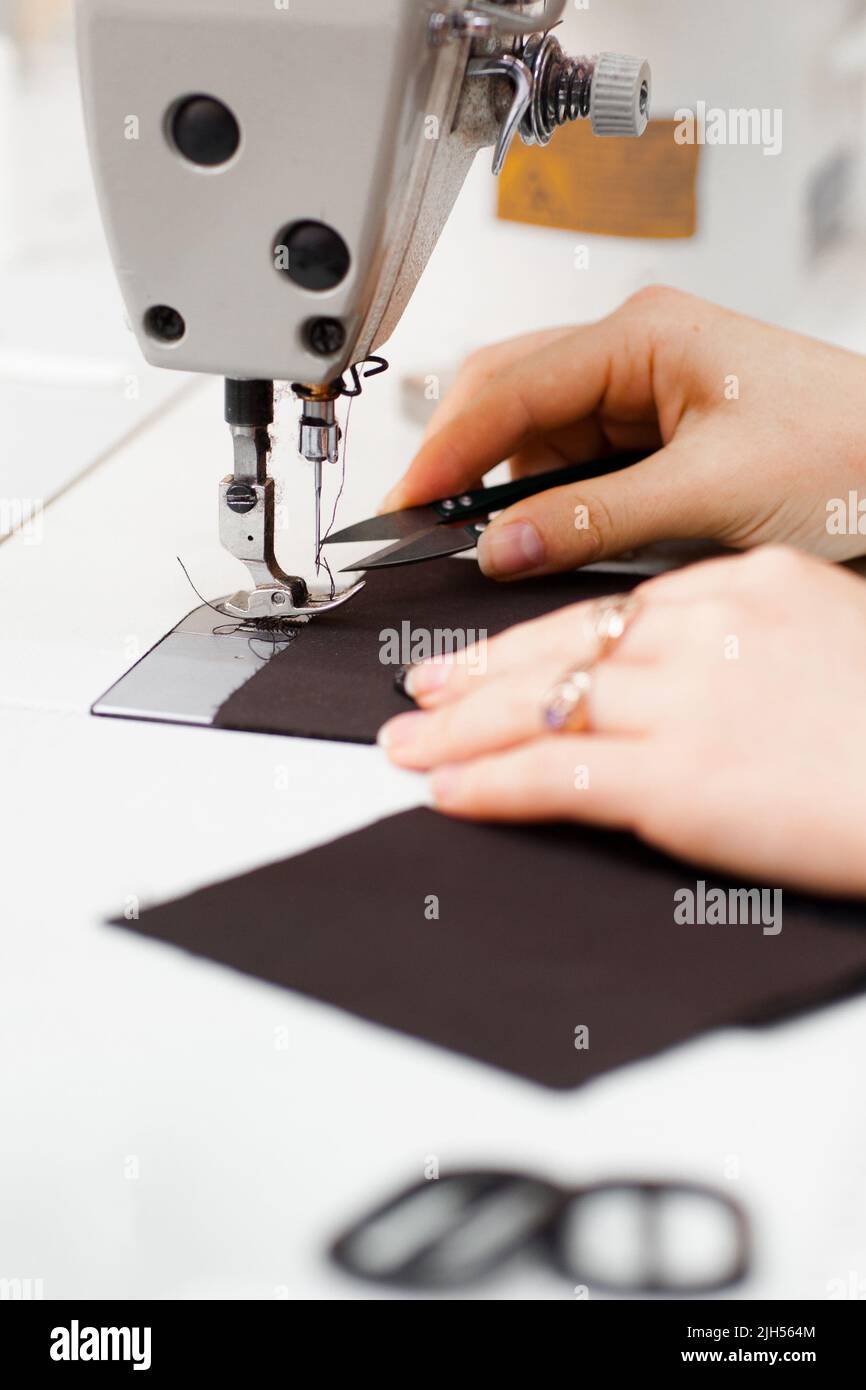 Hands cutting thread on sewing machine side view Stock Photo - Alamy