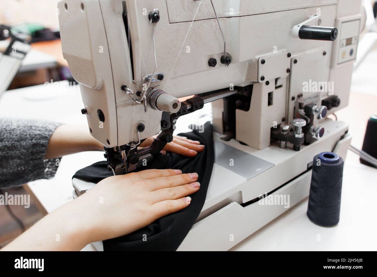 Woman stitching dark fabric on sewing machine Stock Photo - Alamy