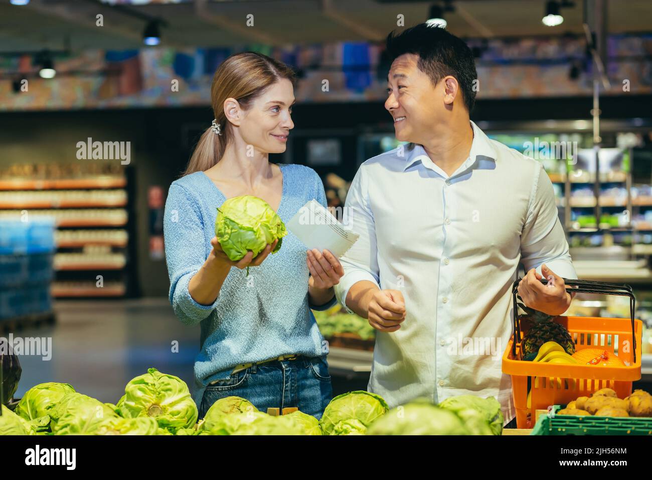 Happy mixed race asian couple family man and woman choosing vegetables ...