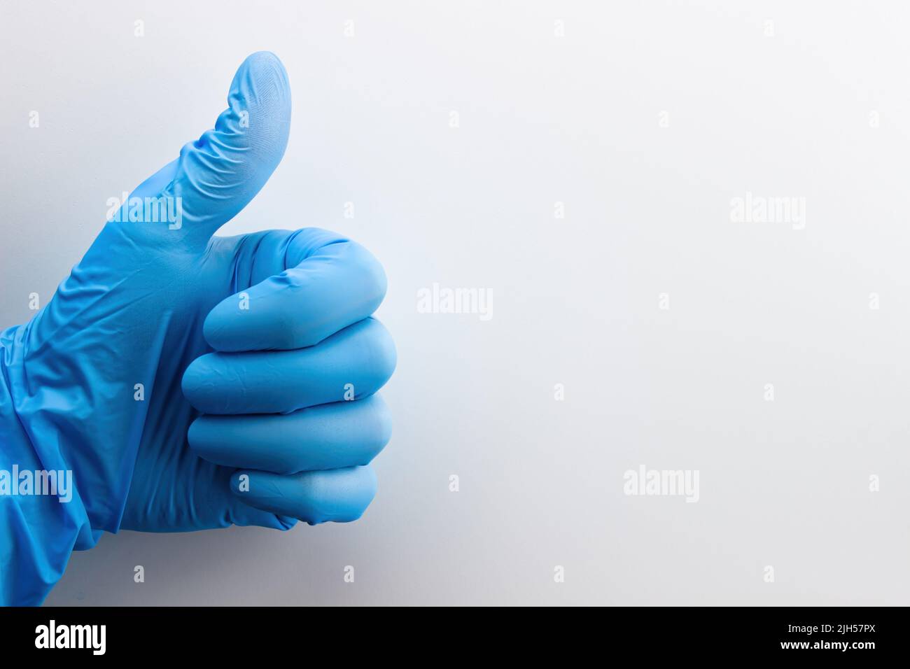Surgeon's hand in blue medical glove showing ok sign on white ...