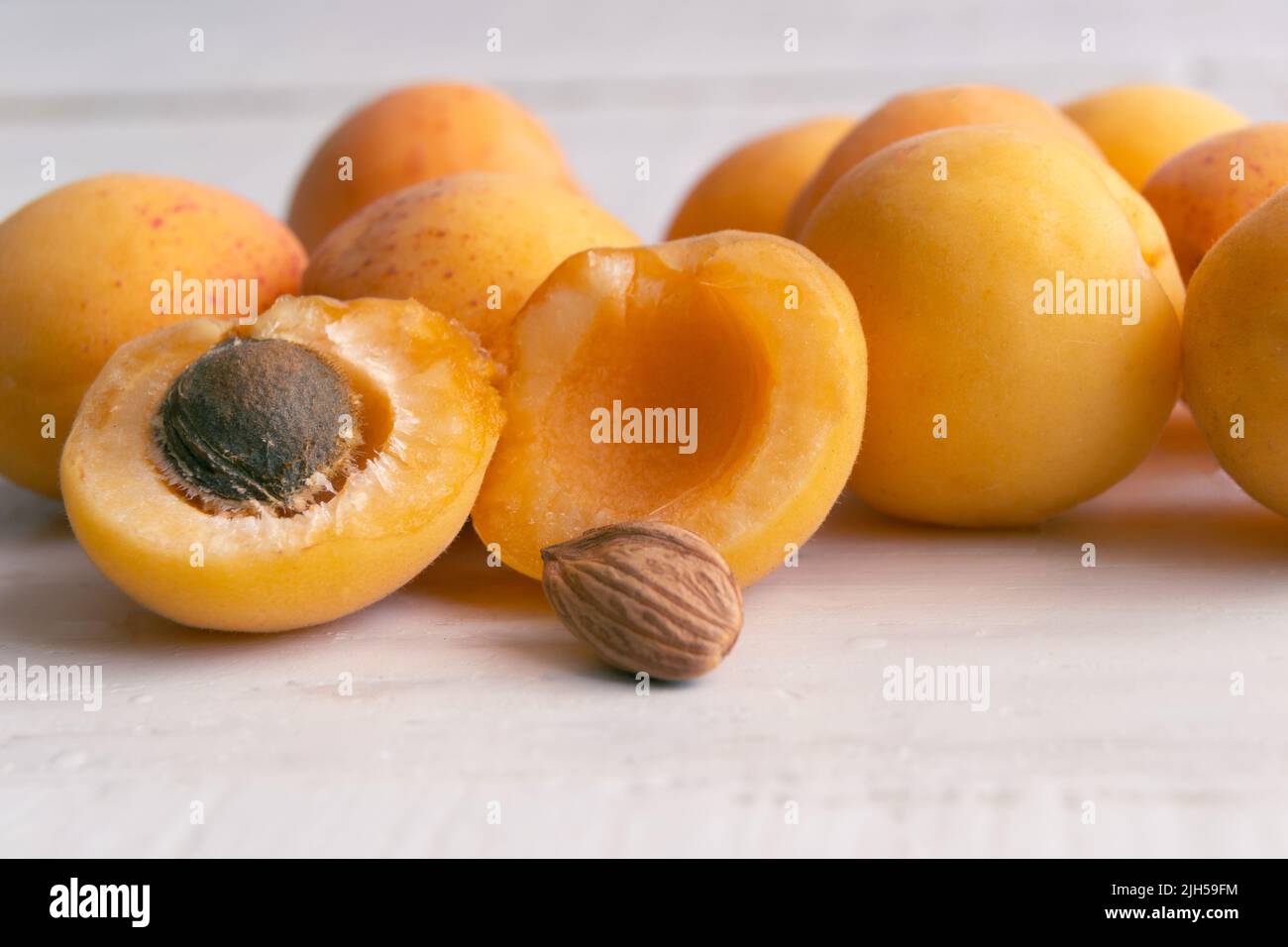 Apricots and kernel on a white wooden background. Apricot seeds Stock ...