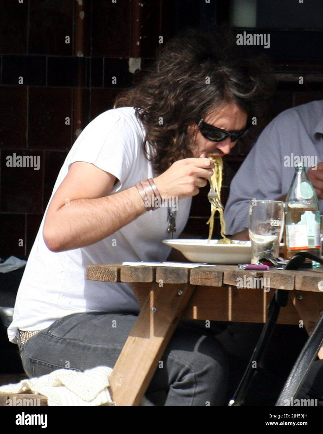 Russell Brand struggles with his spaghetti pub lunch while being ...