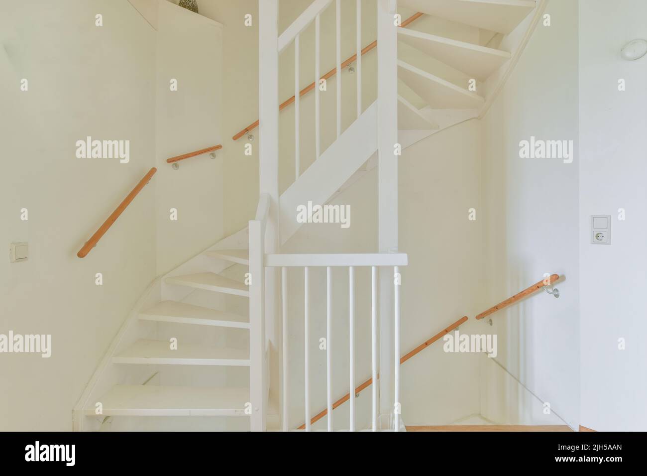 From above of narrow spiral stairway with white stairs and railing on ...