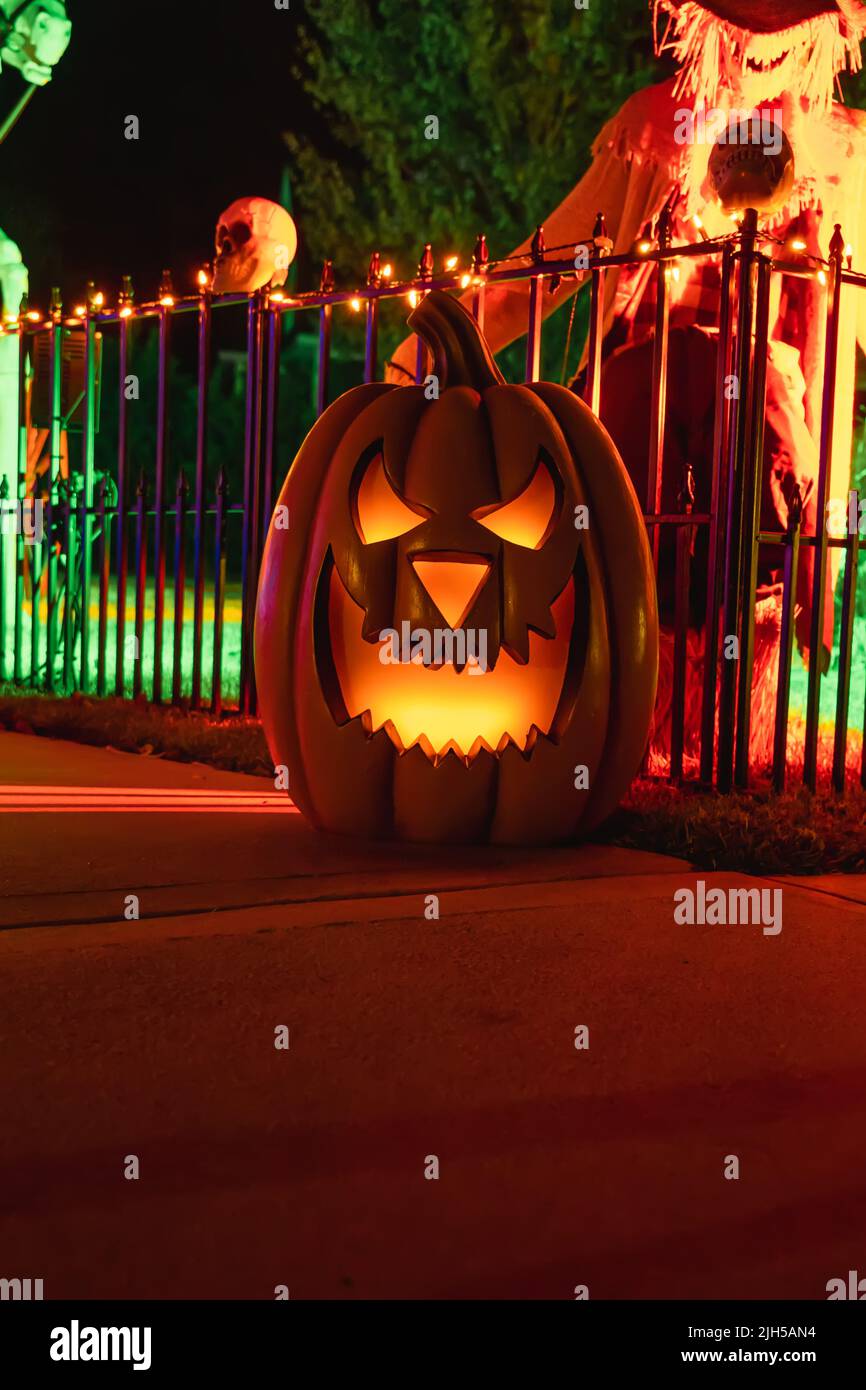 A scary jack-o-lantern pumpkin lit up at night and glowing orange at a ...