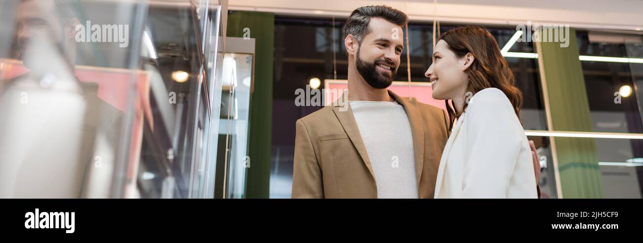 Low angle view of smiling customer hugging girlfriend in jewelry shop ...