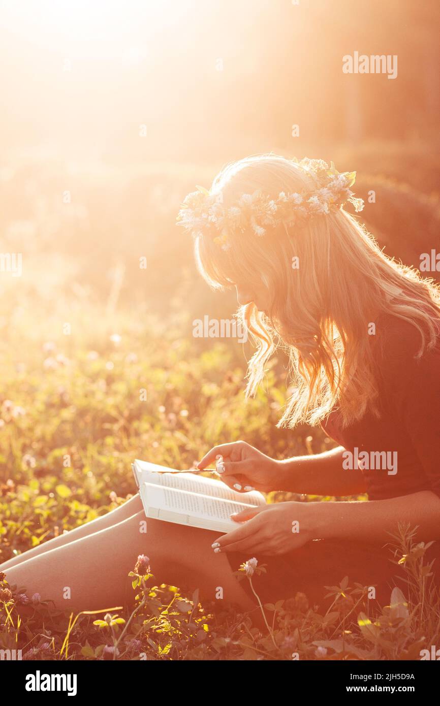 Profile of girl in wreath reading book, sun flare Stock Photo - Alamy