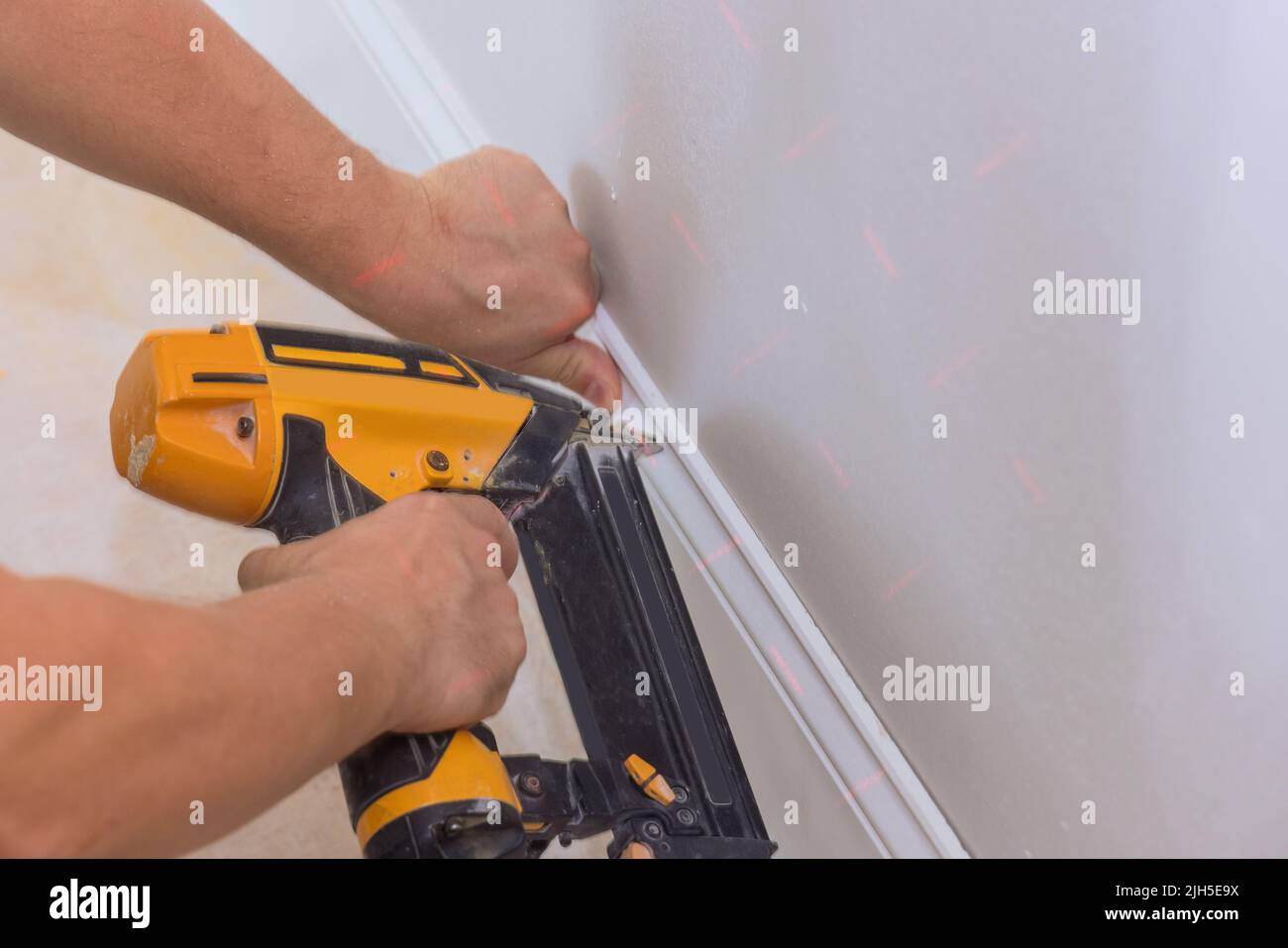 Carpenter using a brad nail gun to nailing base molding trim Stock ...