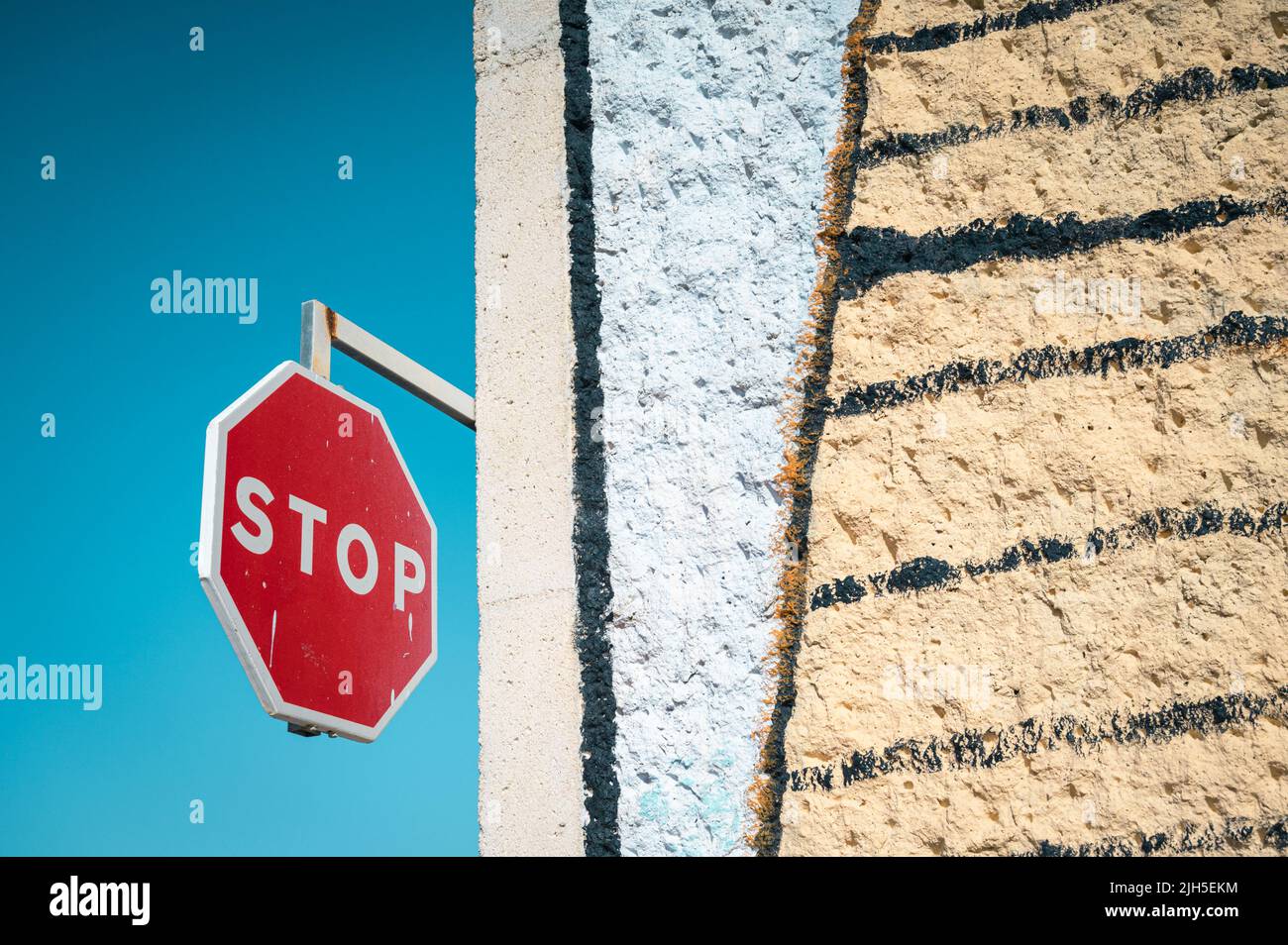 A red stop sign on a wall that has been painted with art work forming a ...