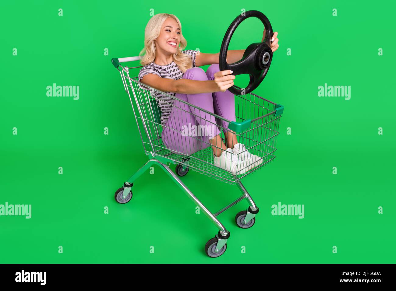 Full size portrait of cheerful lady sitting shop trolley hold wheel ...