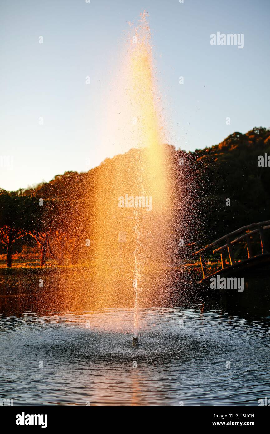 Splashing fountain injected from water surface touching orange sunlight ...