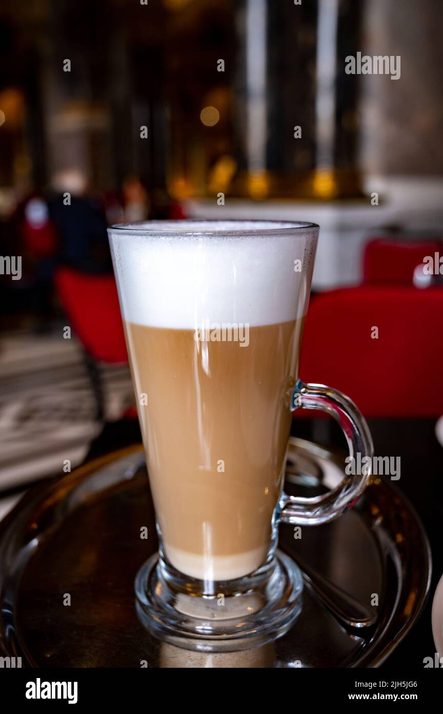 Glass cup of coffee latte served in classic old Austrian café ...