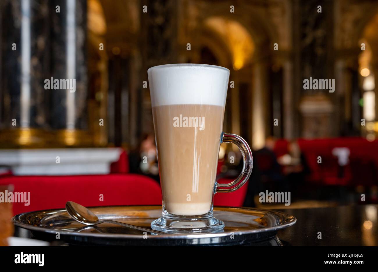 Glass cup of coffee latte served in classic old Austrian café ...