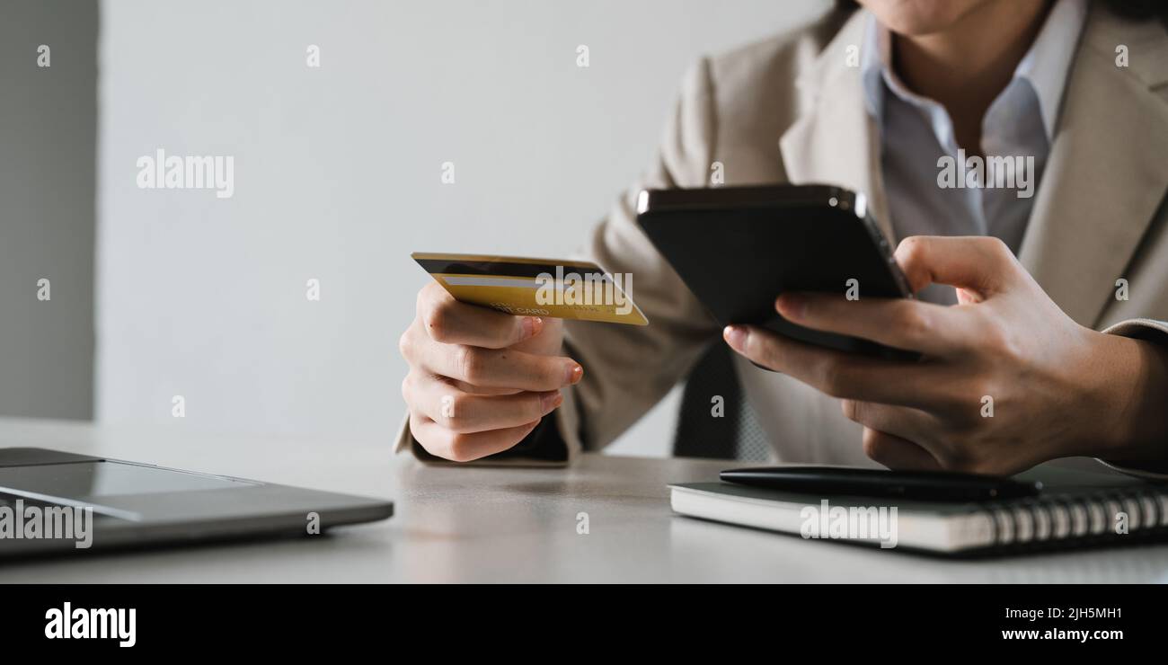 Close up female hands holding credit card and smartphone, young woman paying online, using ...