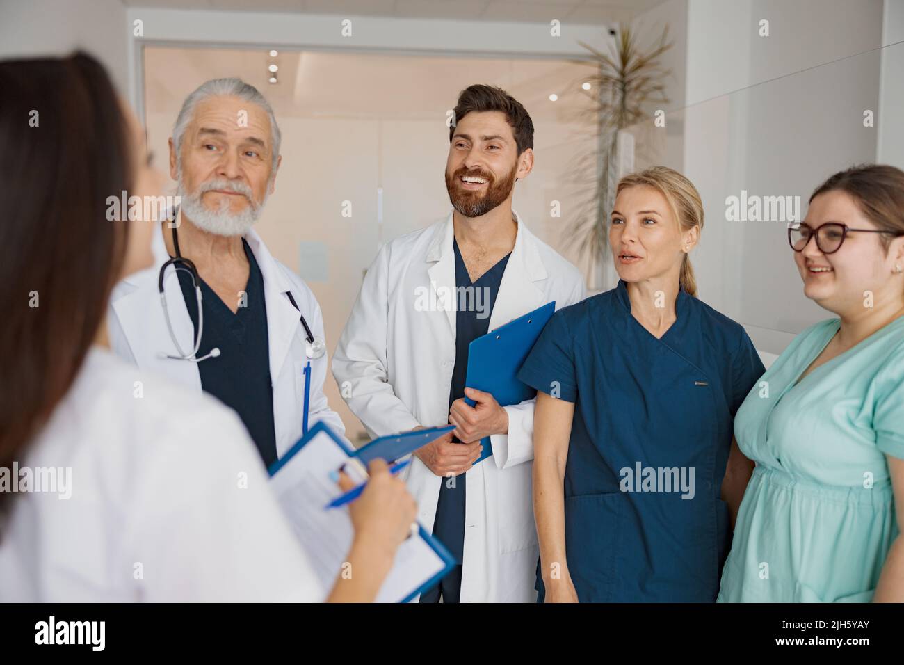 Group of doctor colleagues discussing patient diagnosis stand in clinic ...