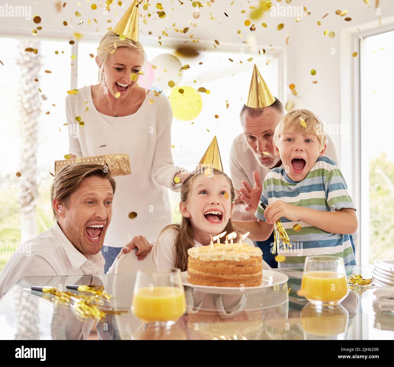 Cheerful generational happy family wearing party hats while celebrating ...
