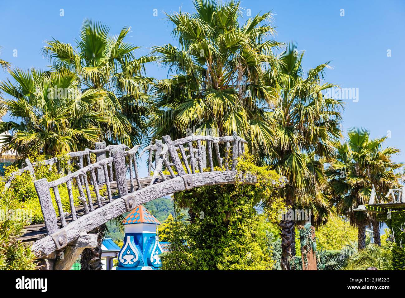 Wooden ruined bridge among tropical palm trees in amusement park ...