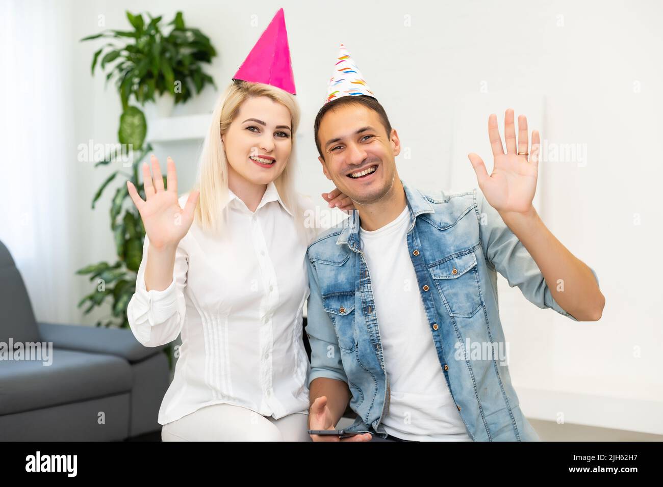 Young couple or friends in party hats having fun virtual celebration ...