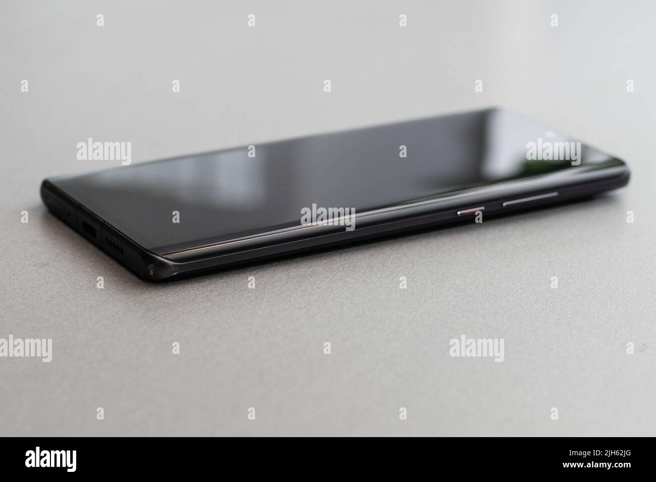 Black modern mobile phone with blank screen on black stone table ...