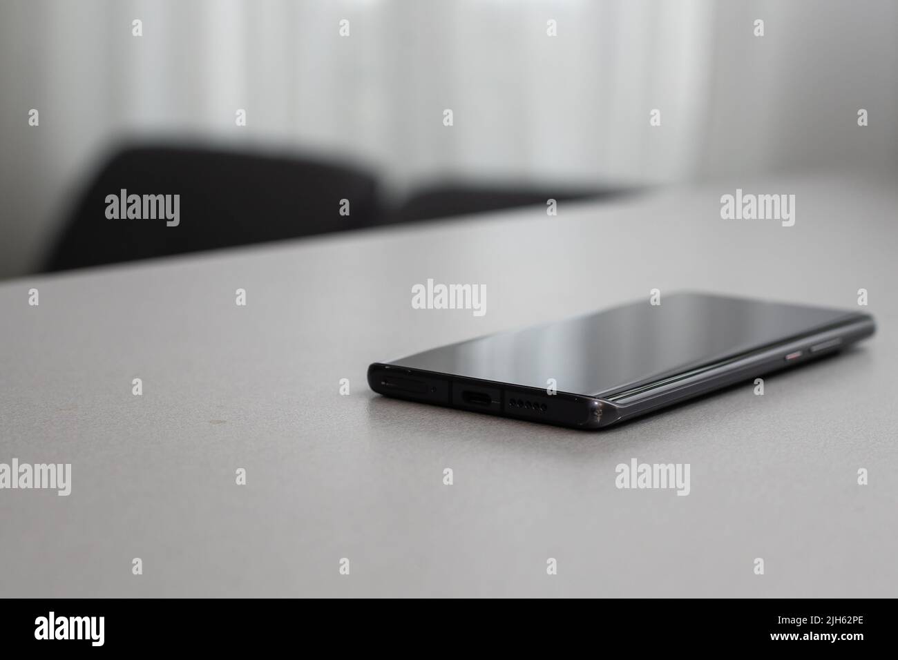 A single mobile phone on gray table Stock Photo - Alamy
