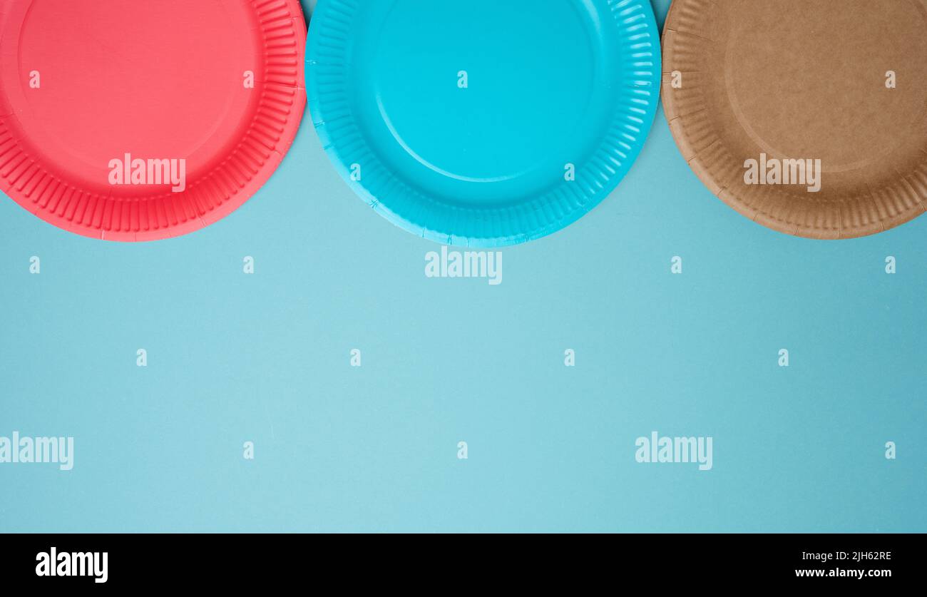 Empty paper disposable plates on a blue background, top view. The ...