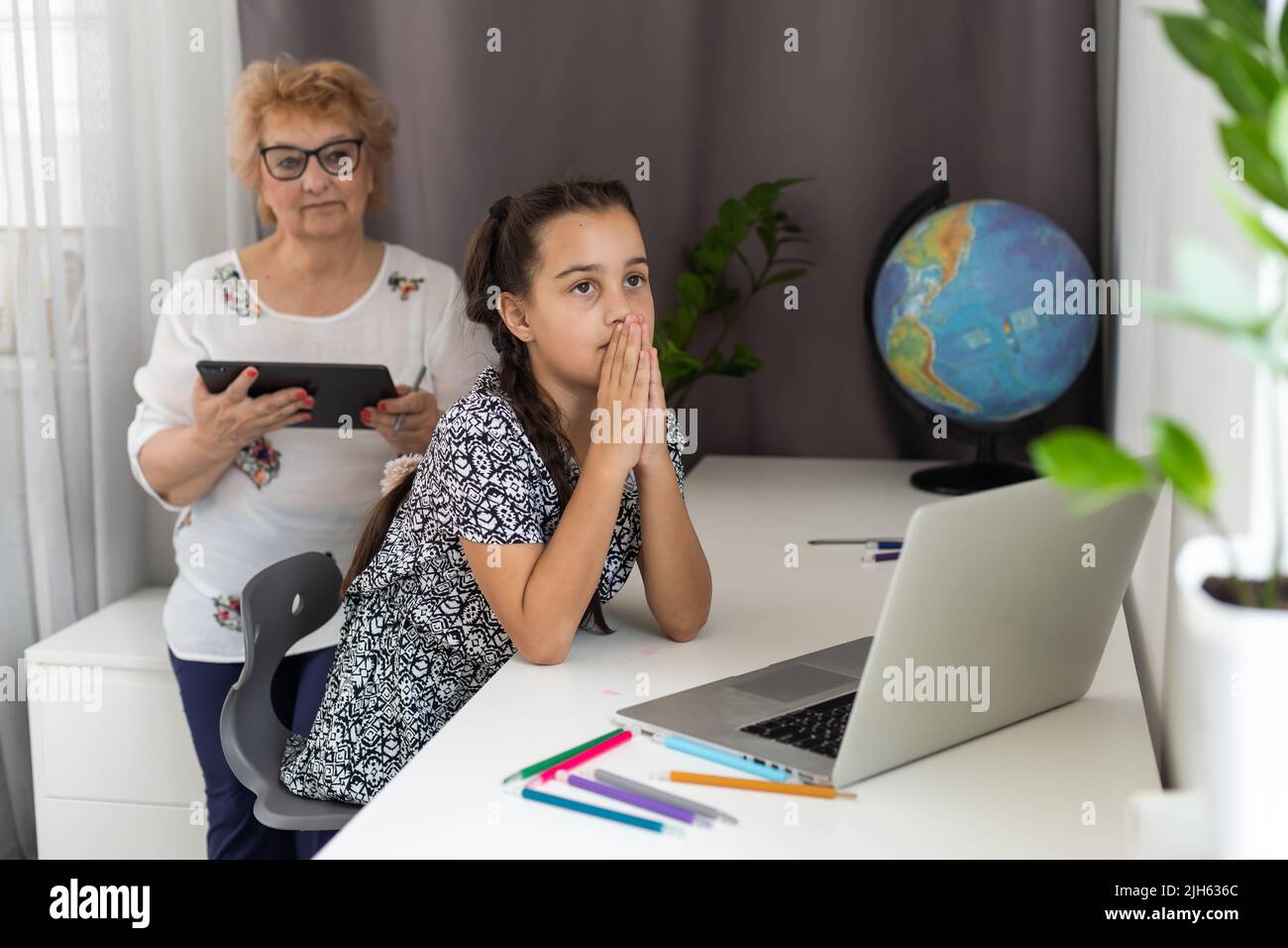 Older woman grandma and little girl grandkid with homework remote study ...