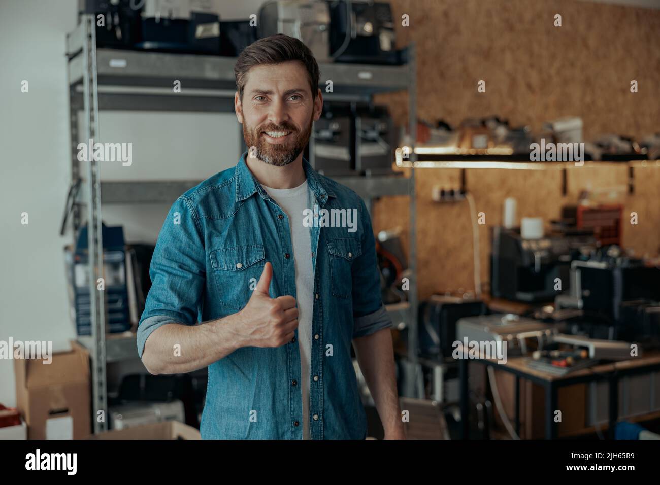Business owner standing on workshop of coffee machines warehouse with ...