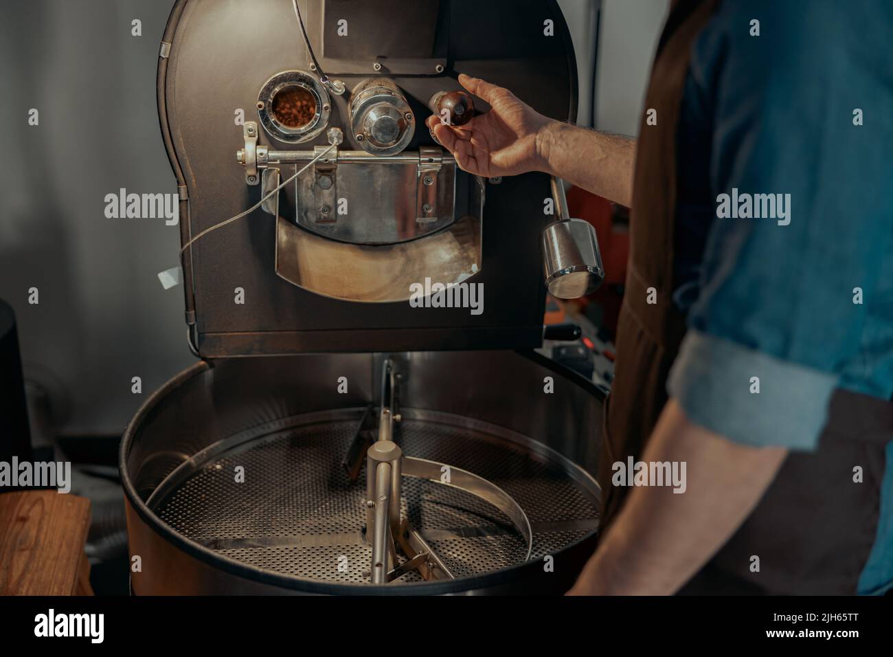Close up of business owner hands operating modern coffee bean roasting ...