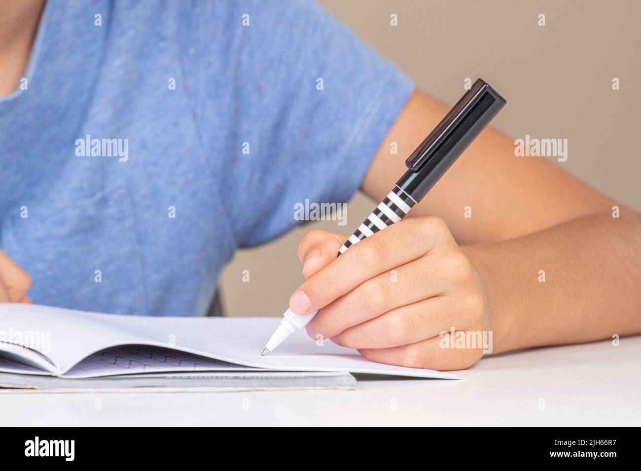 Kid holding pen in left hand and doing homework, writing in open ...