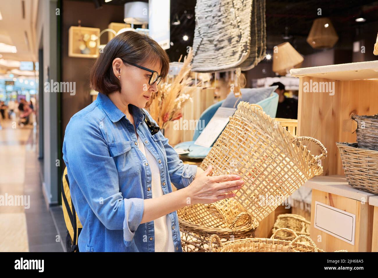 Mature woman shopper choosing interior wicker baskets in home decor ...