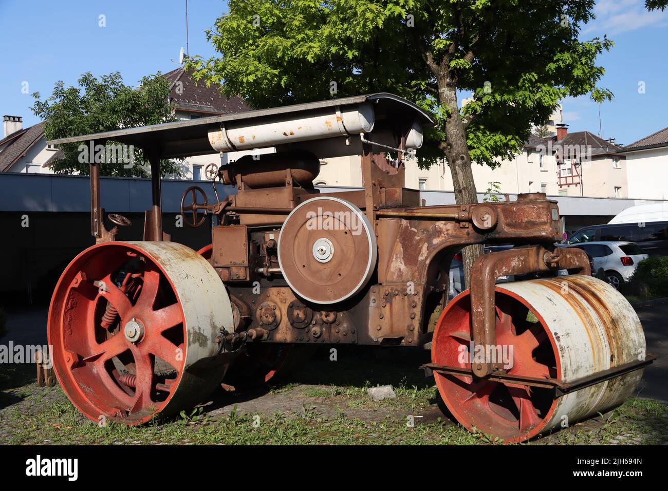ancient kind of steam roller under green tree. not functioning any ...