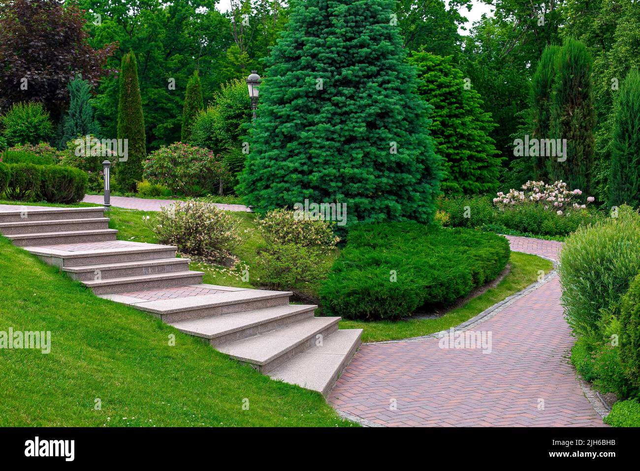 stone steps to path from paving slabs in park on slope with ornamental ...