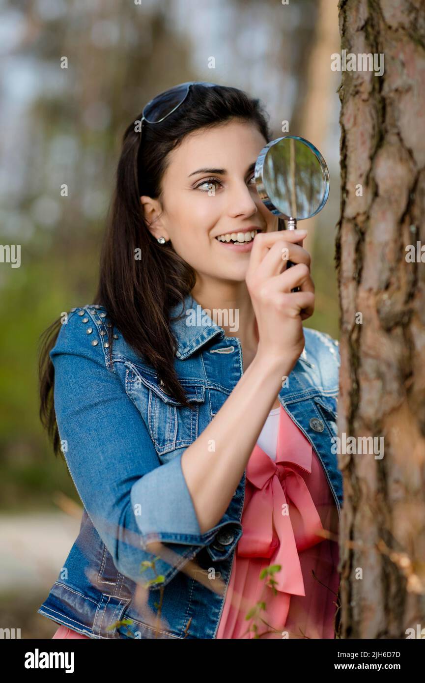 Woman looks at tree trunk under the magnifying glass Stock Photo - Alamy