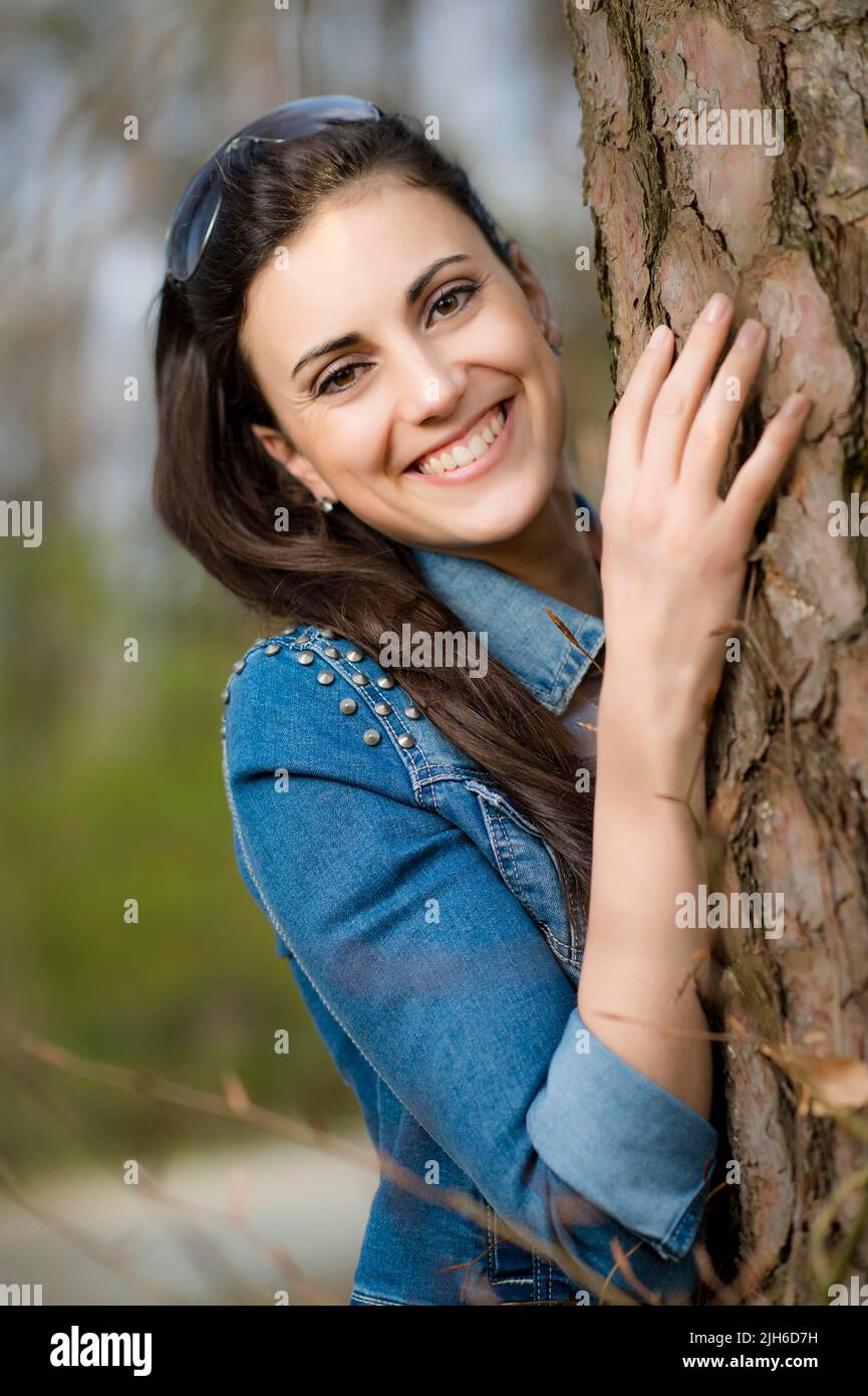 Woman leaning against tree trunk Stock Photo - Alamy