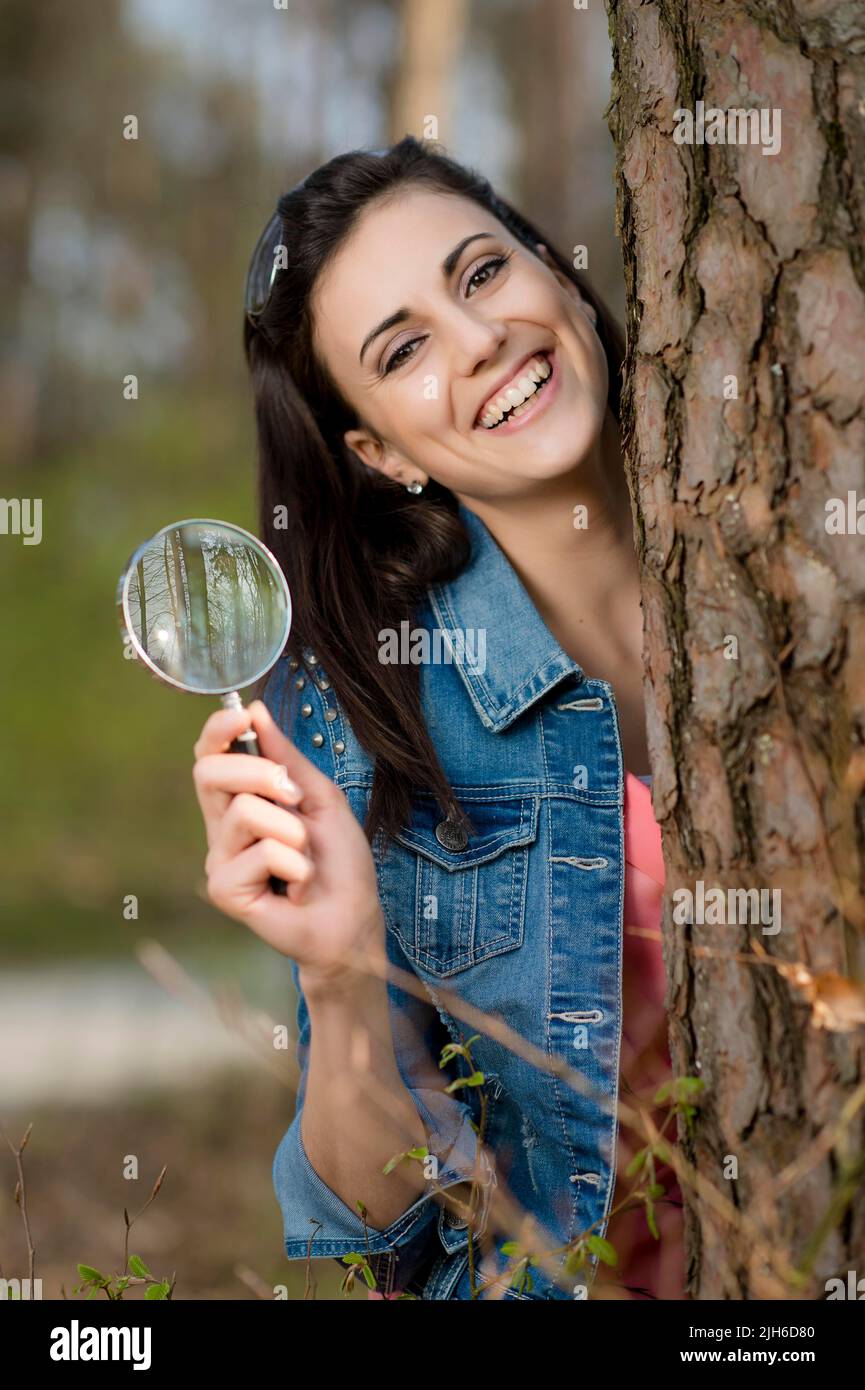 Woman looks at tree trunk under the magnifying glass Stock Photo - Alamy
